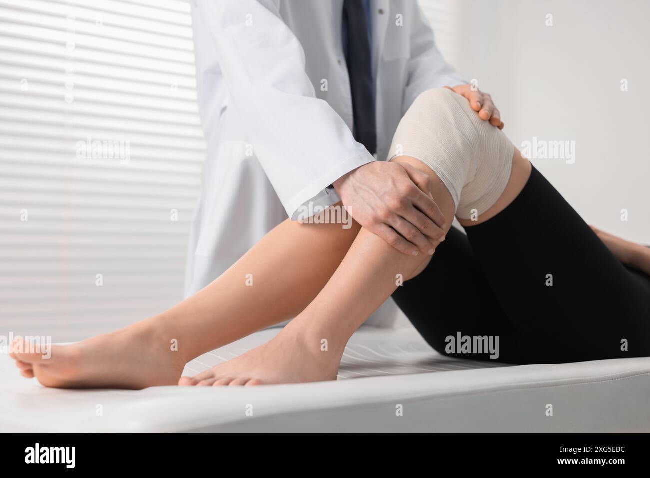 Sports injury. Doctor examining patient's knee in hospital, closeup ...