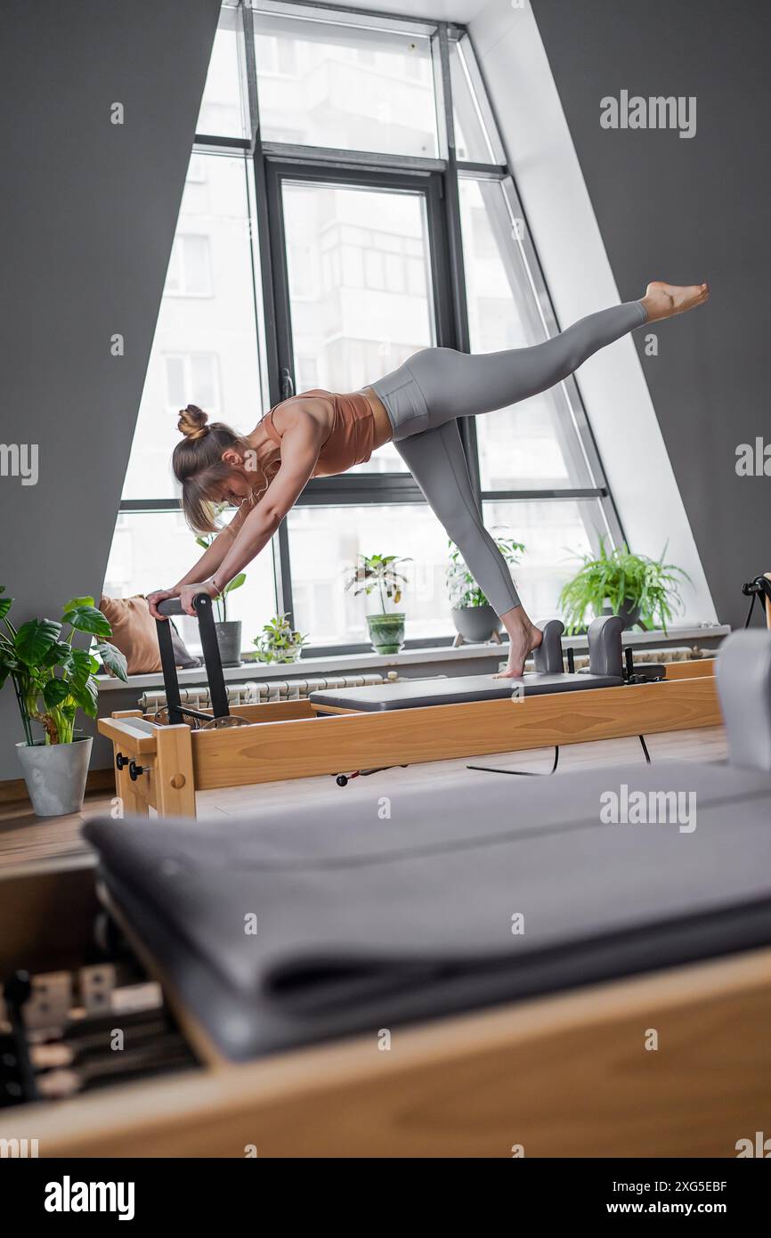 Woman doing Pilates exercise for core and back muscles on Reformer ...