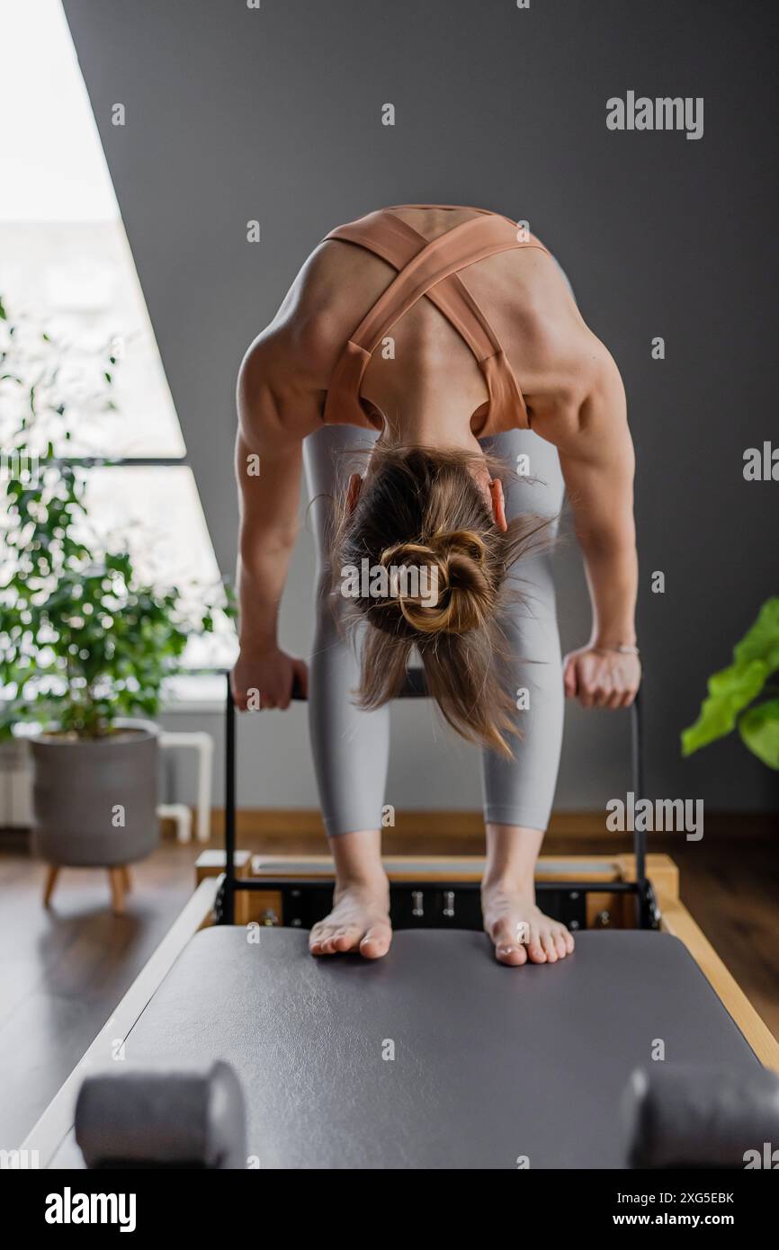 Woman doing Pilates exercise for core and back muscles on Reformer ...