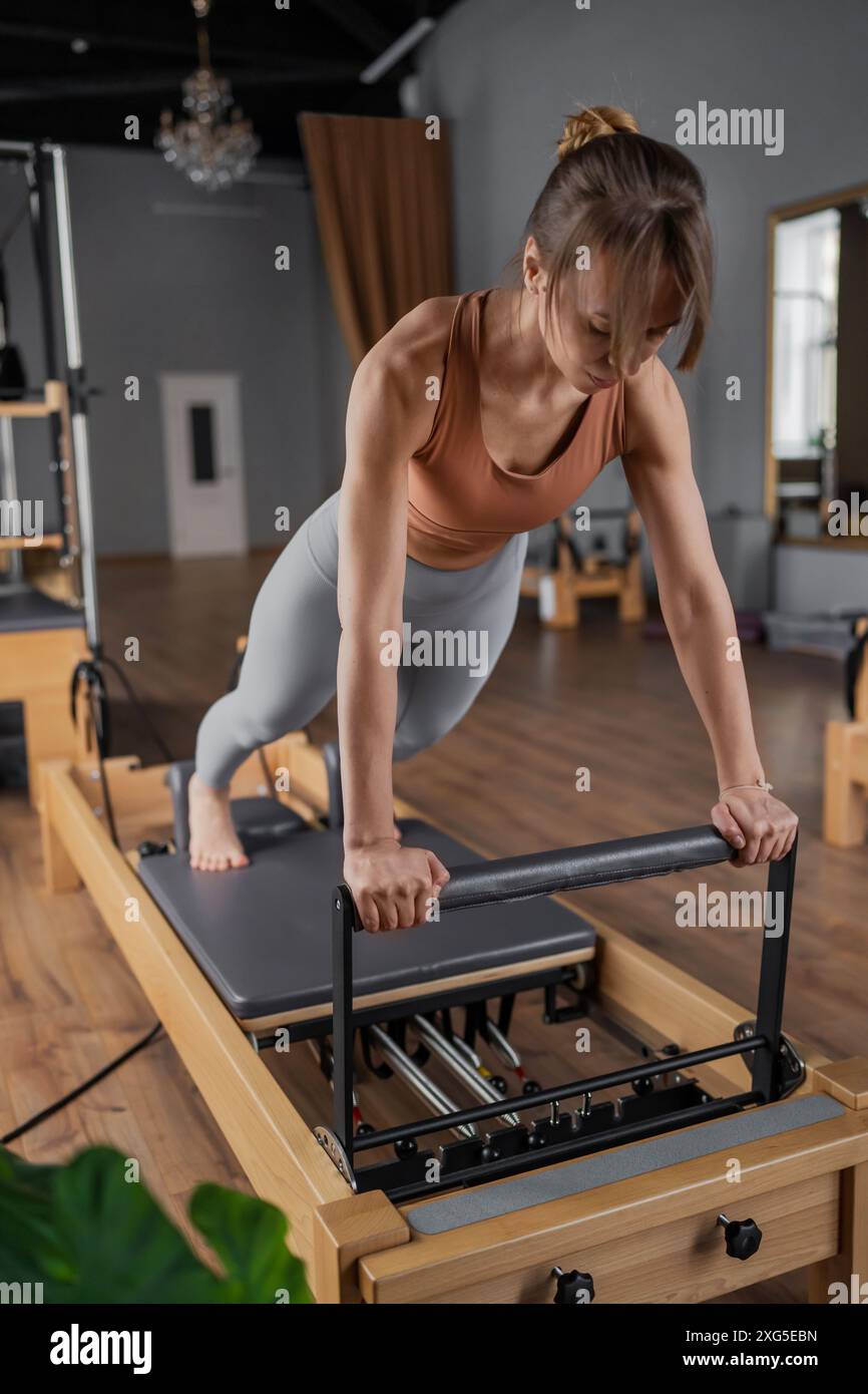 Woman doing Pilates exercise for core and back muscles on Reformer ...