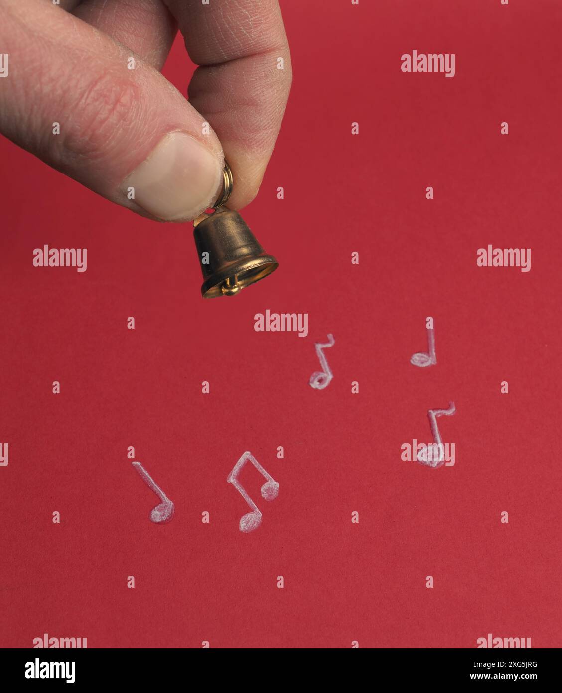 Hand with a bell on a red background Stock Photo - Alamy