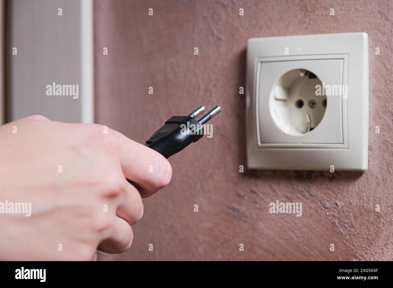Euro socket woman's hand inserts an electric plug into a socket, close ...