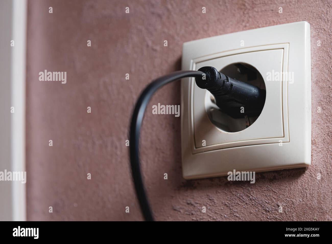 Close-up of a black electric plug in a 220 socket in the wall. Power on ...