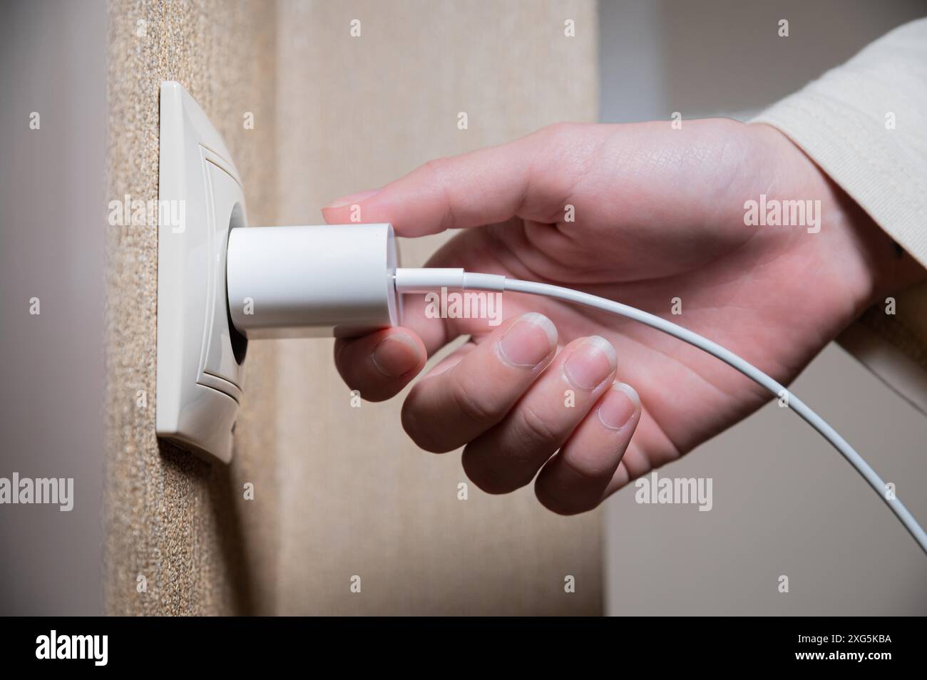 Close-up of a woman's hand inserting a white usb charger into a 220 ...