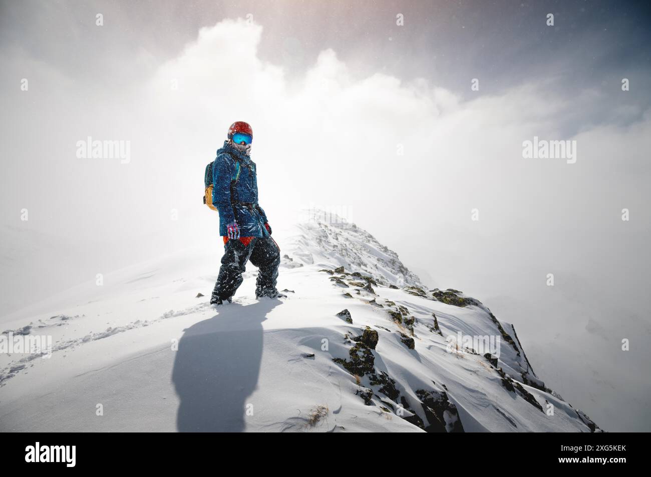 Portrait of a brave man standing on a snowy mountaintop, wearing ski ...