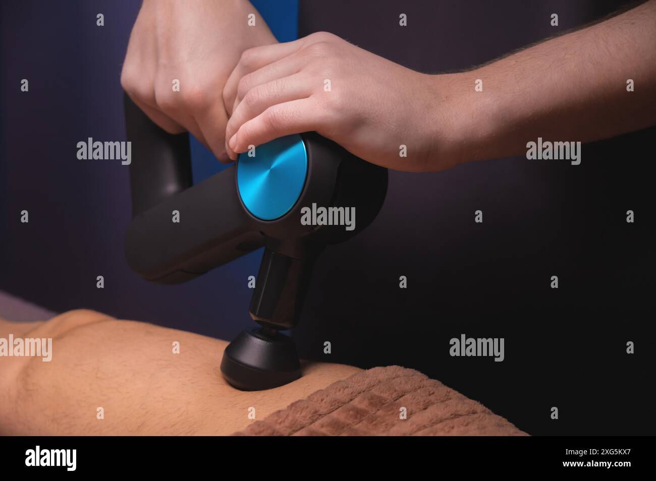 Percussion massage of the athlete's leg, close-up, hands holding a tool ...