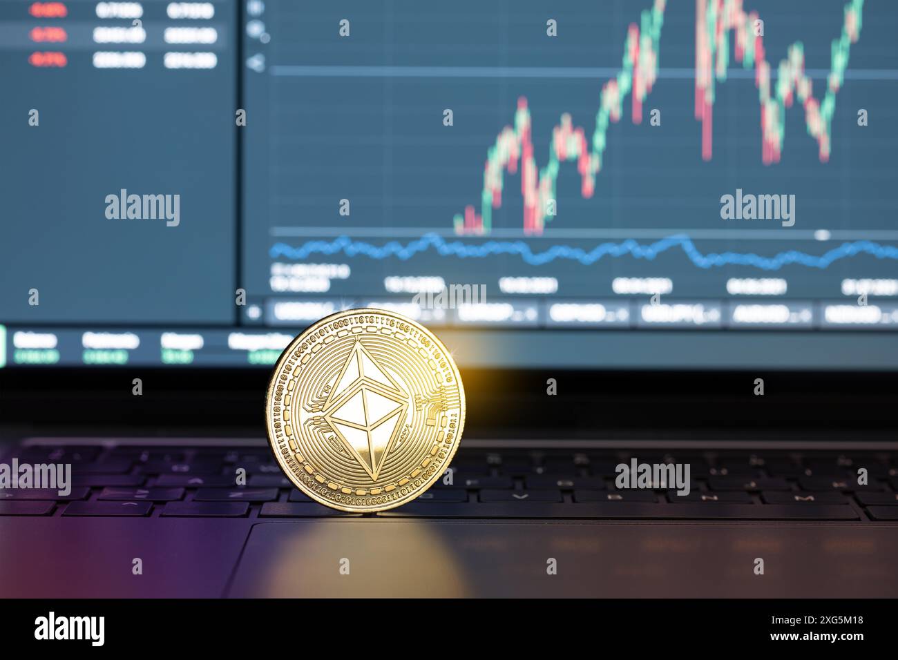 Ethereum coin on laptop and chart on display at background ...