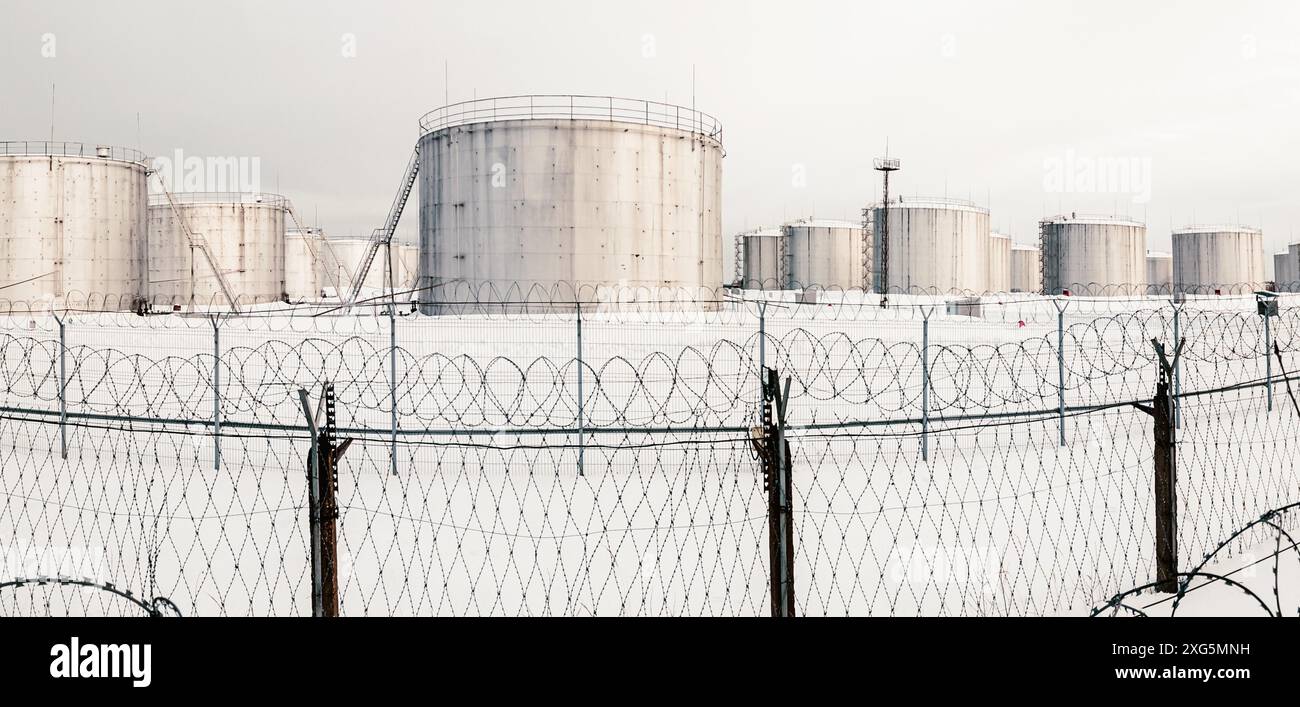 Gas storage tanks in winter, tank farm behind a fence topped with ...