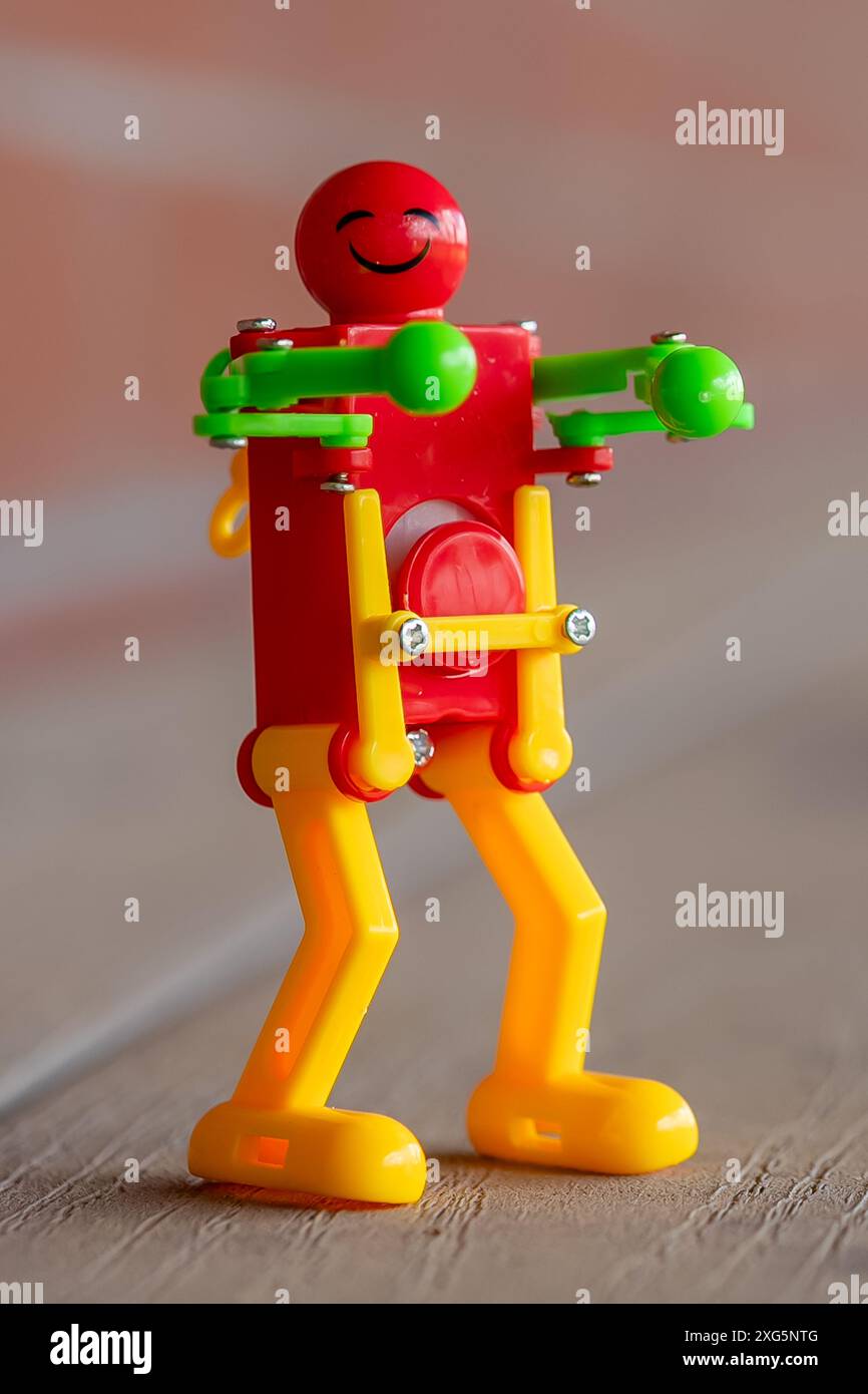Vertical photo of a funny plastic toy robot doing a happy dance ...