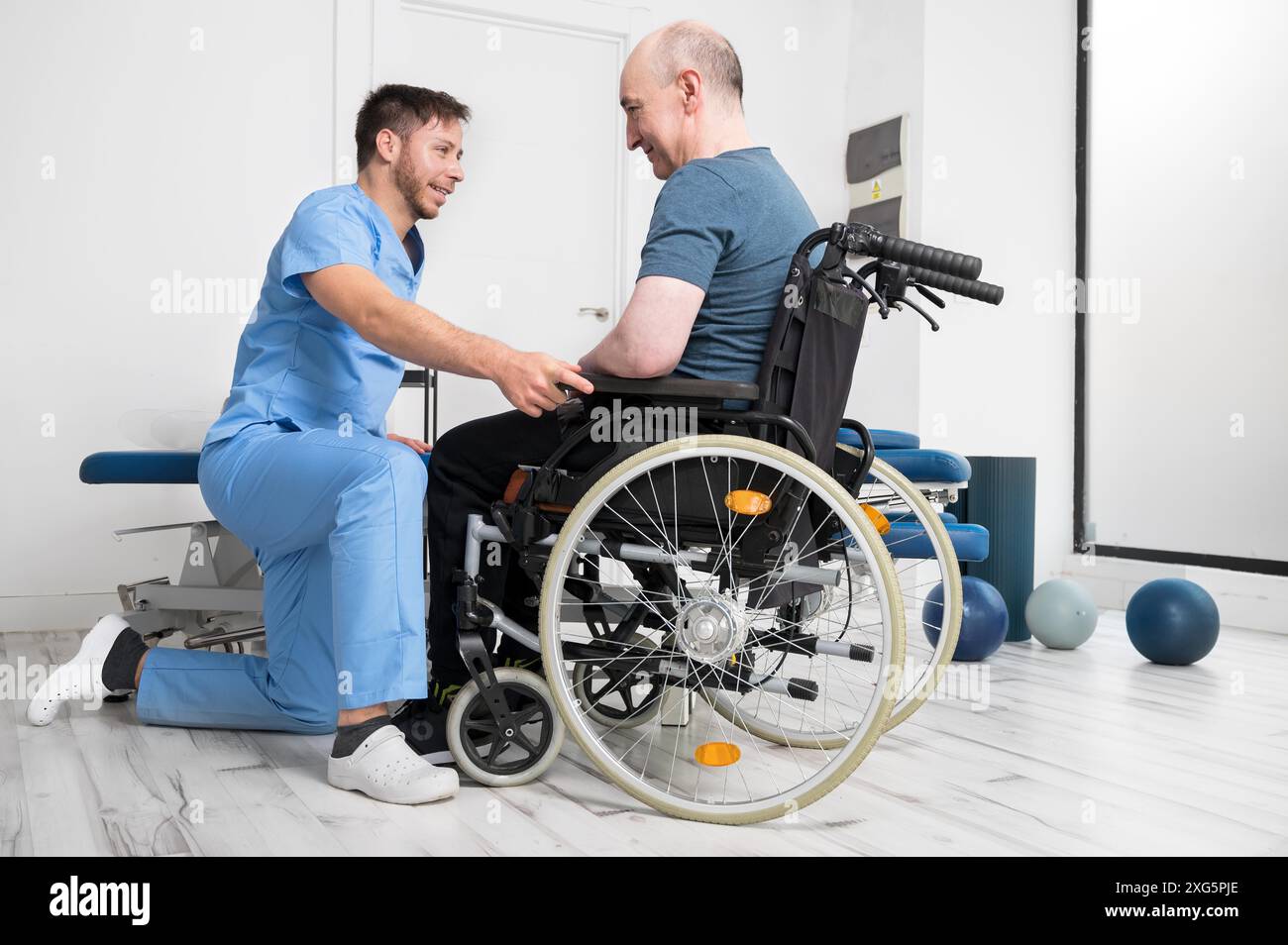 Male Physiotherapist helping a patient with a disability who uses a ...
