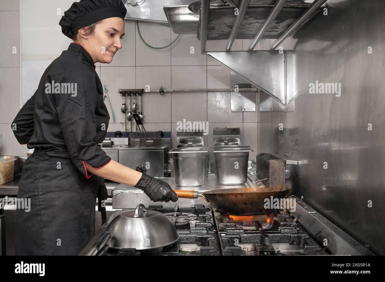 Side view of female chef working in commercial kitchen. High quality ...