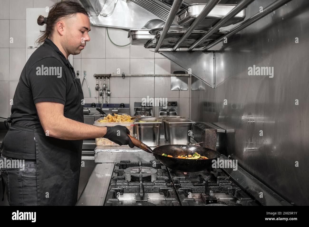 Side view of male chef working in commercial kitchen. High quality ...