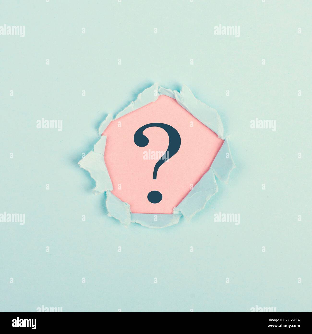 Question marks on pink colored torn paper, light blue background ...