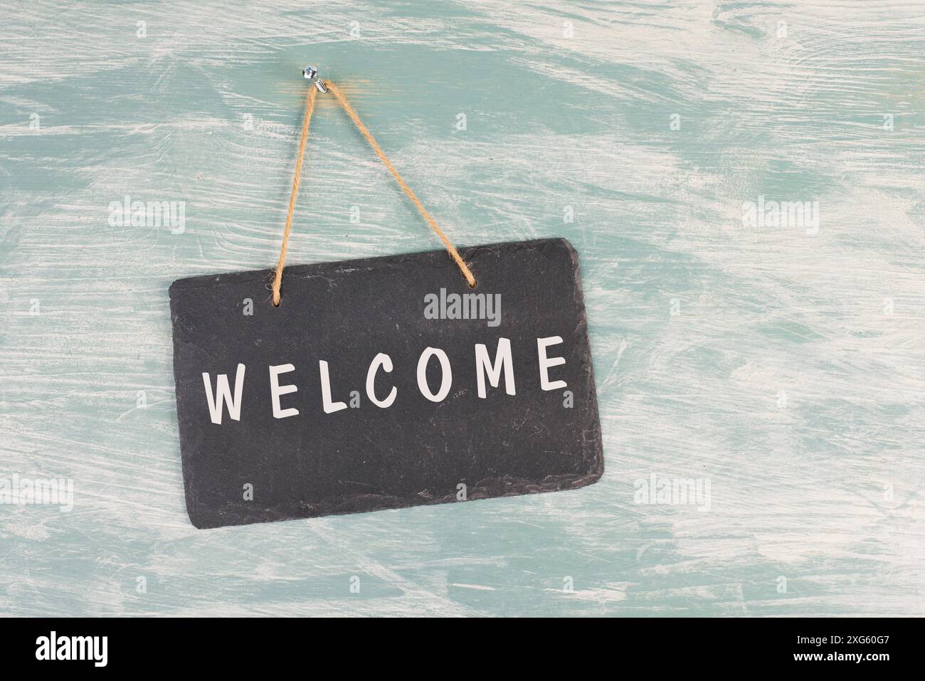 The word welcome is standing on a chalkboard sign, hanging on a blue ...