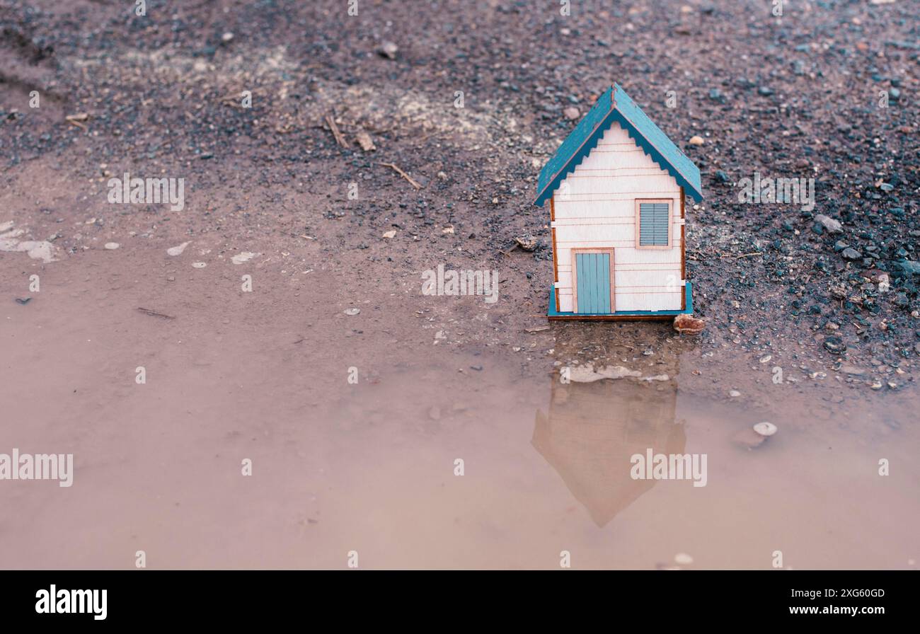 Small house standing on a road with a big puddle, real estate concept ...