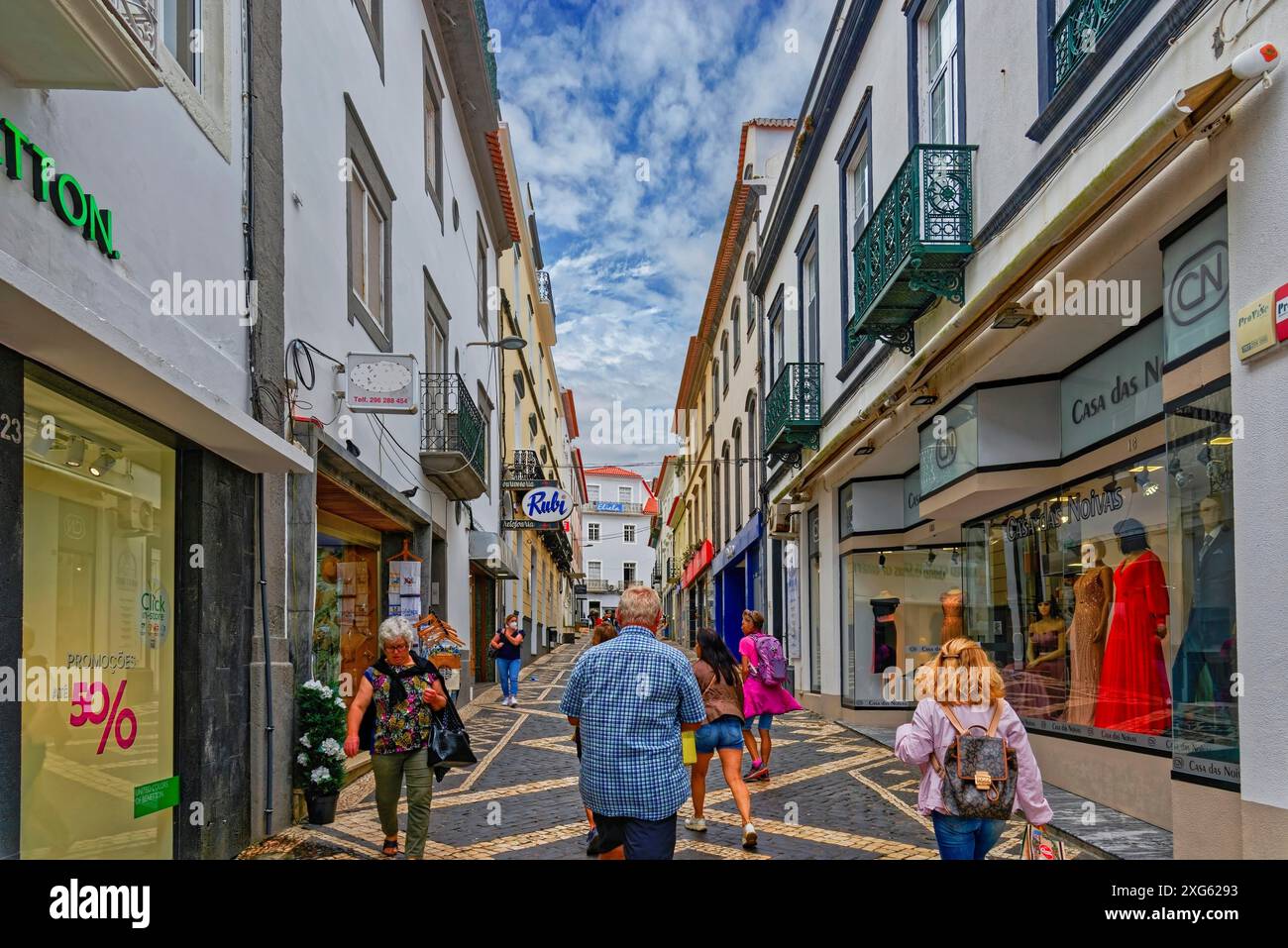 People walk through a busy shopping street with modern shops and ...