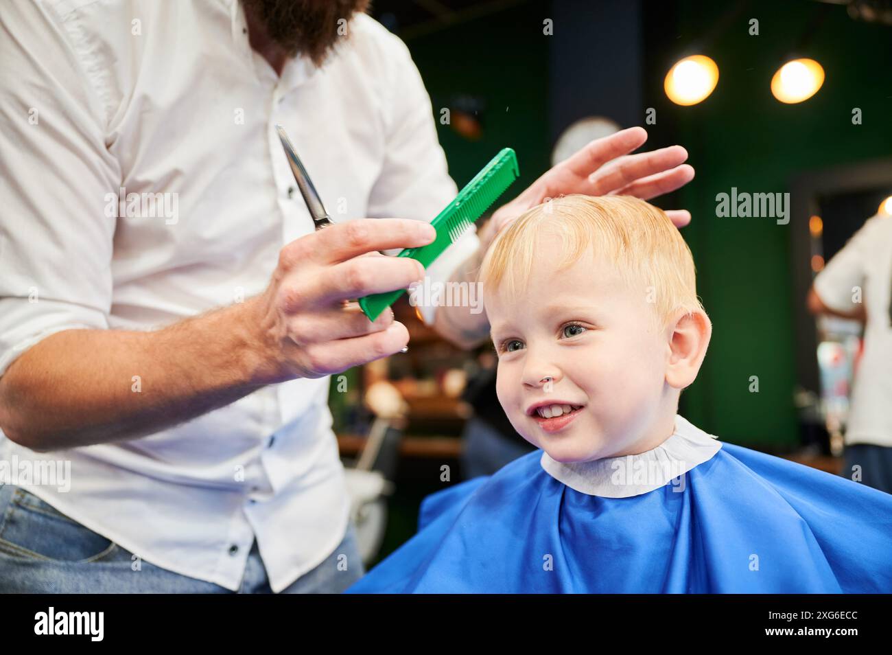 Man barber cutting little boy's hair using comb and scissors. Child ...