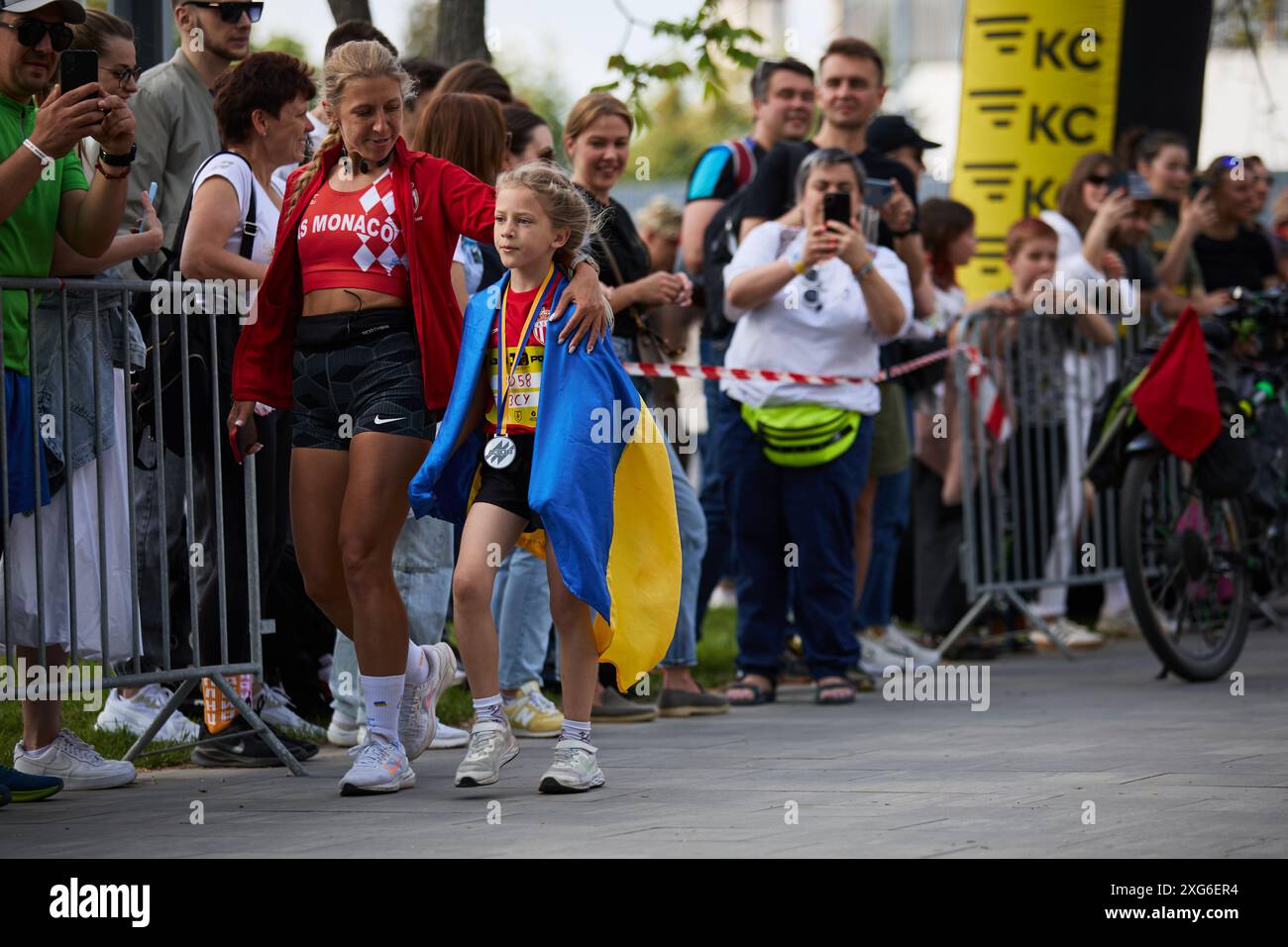 Ukrainian runners at a charity run. Mother embraces her little daughter ...