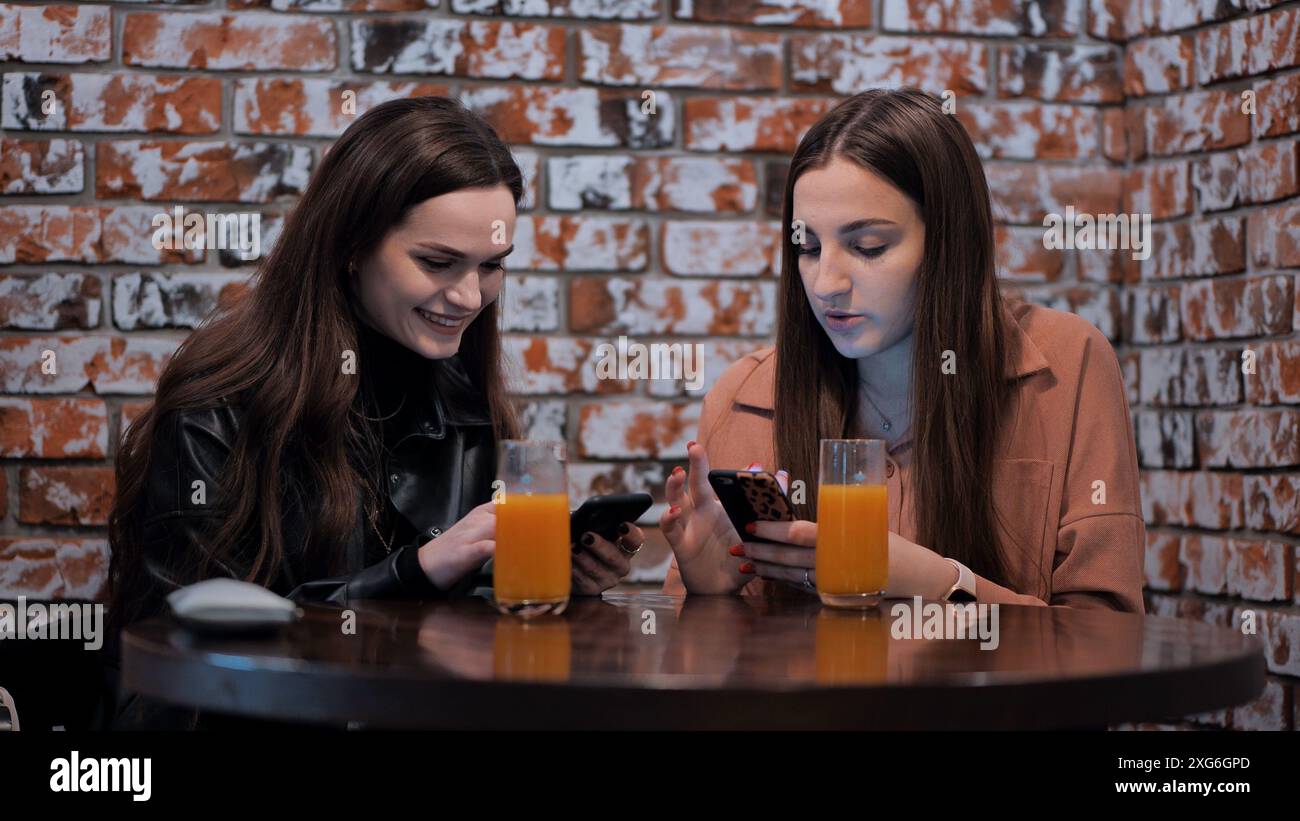 Two beautiful girls students have lunch in a city cafe and write a ...