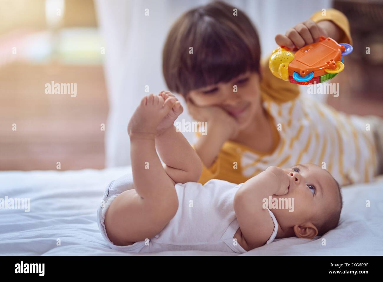 Brothers, baby and playing with toy on bed for bonding, fun activity ...
