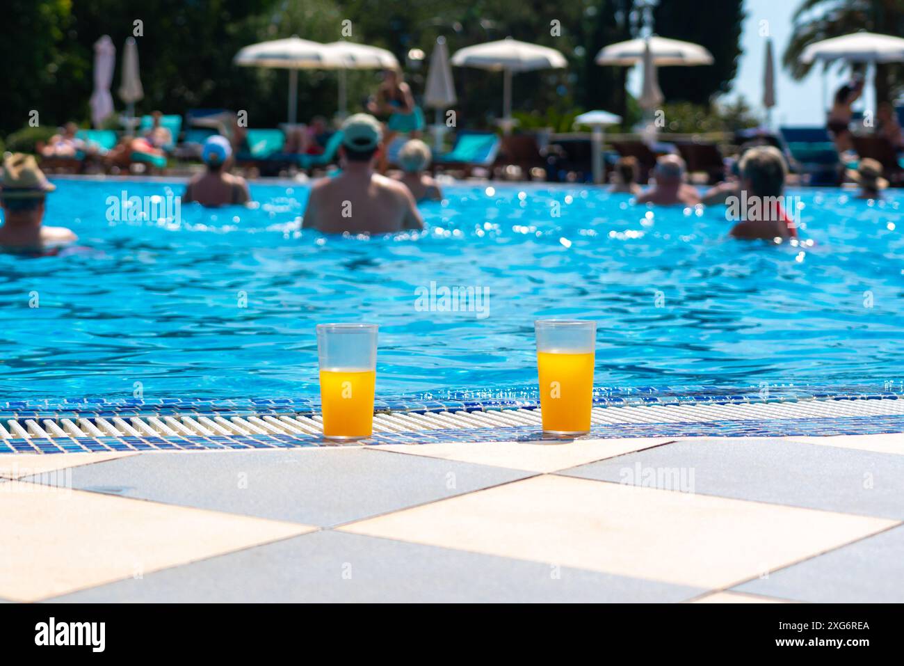 Glass of fresh cool orange juice drink next to swimming pool Stock ...