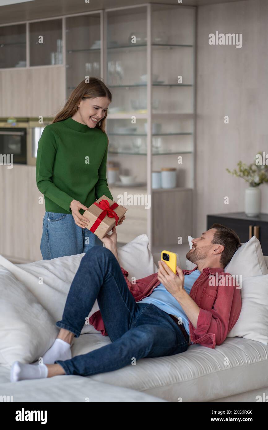 Happy young couple making each other happy with gifts. Joyous girl ...