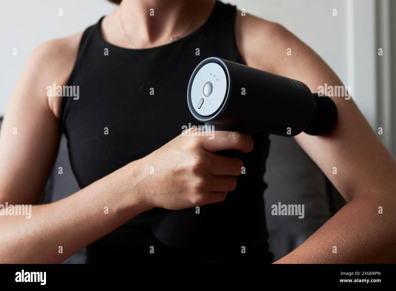 Applying therapeutic percussive massager gun at home Stock Photo - Alamy
