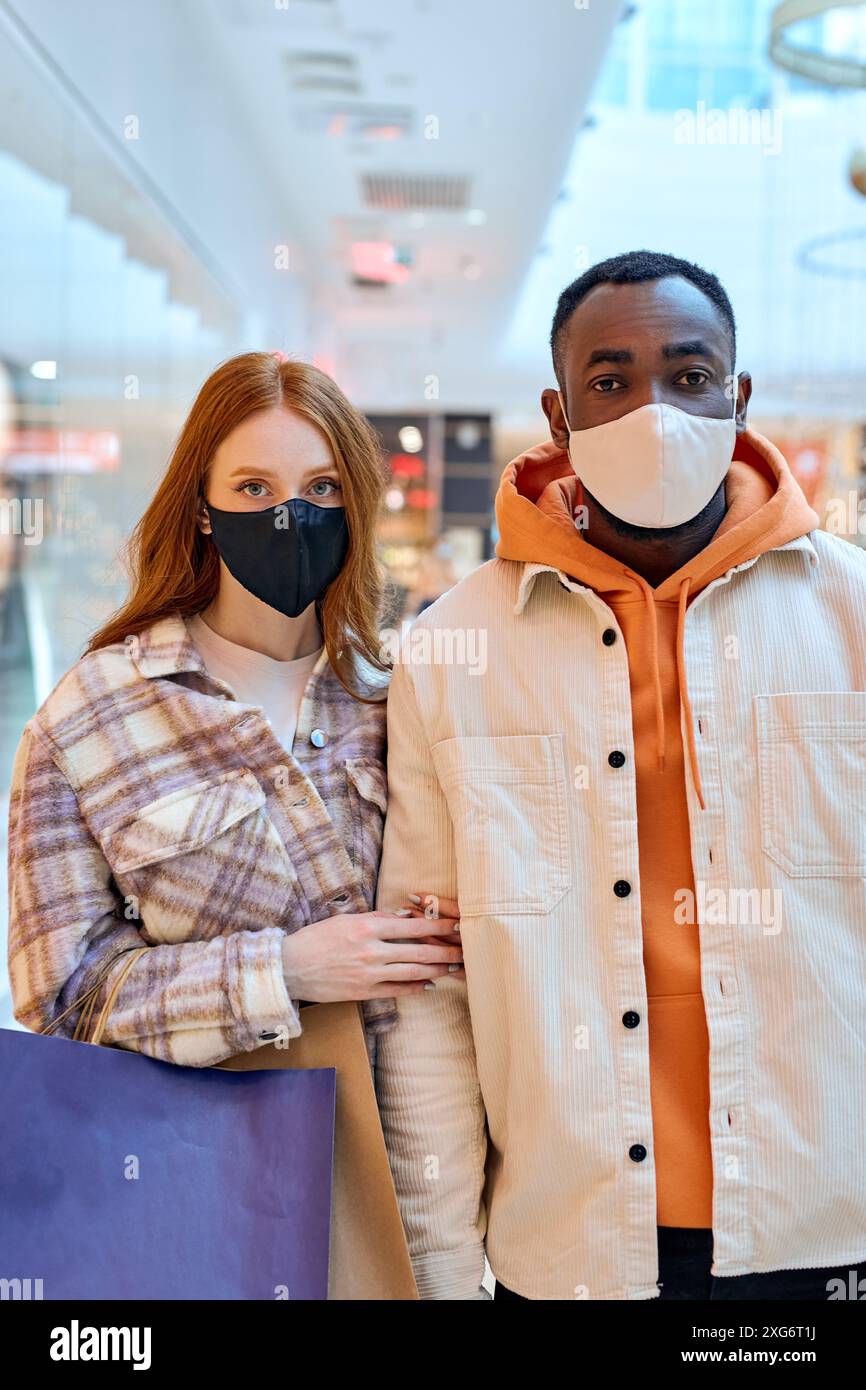 serious diverse couple standing at mall, looking at camera, health care ...