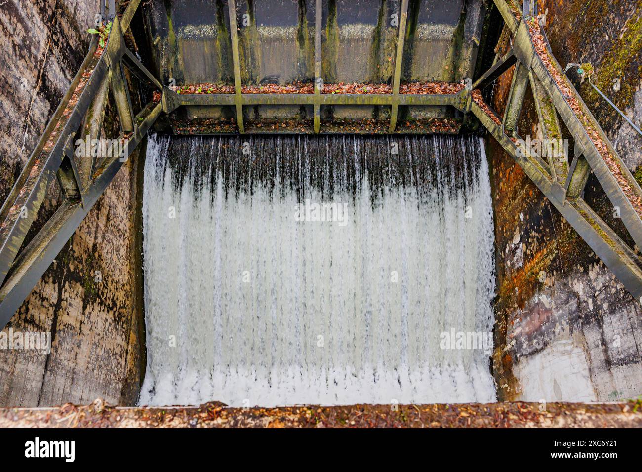 Mechanical hydraulic gate at Robertville Dam with water flowing between ...