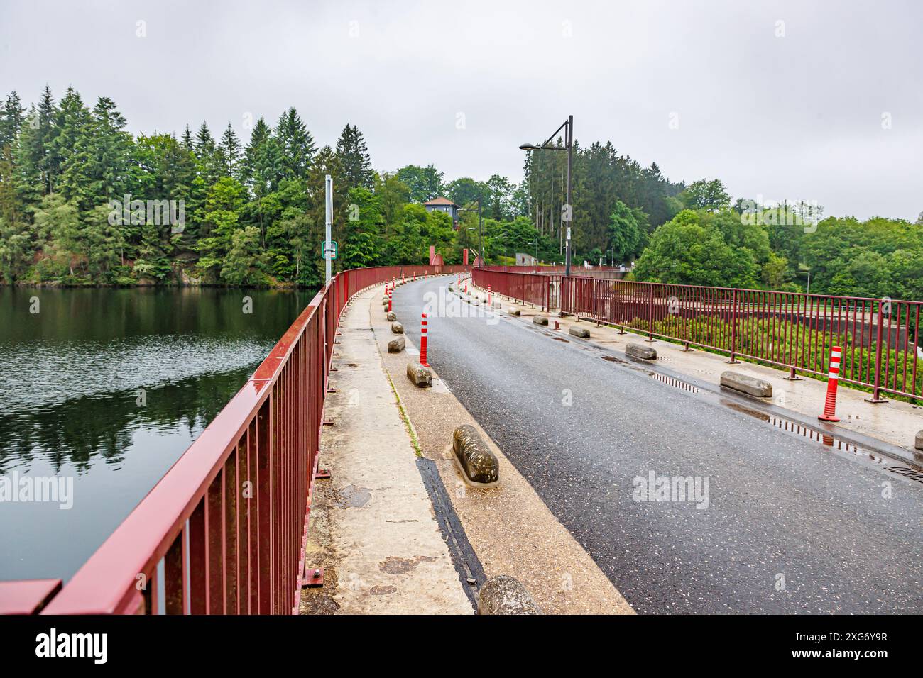 Empty country road passing over Robertville Dam wall along lake, leafy ...