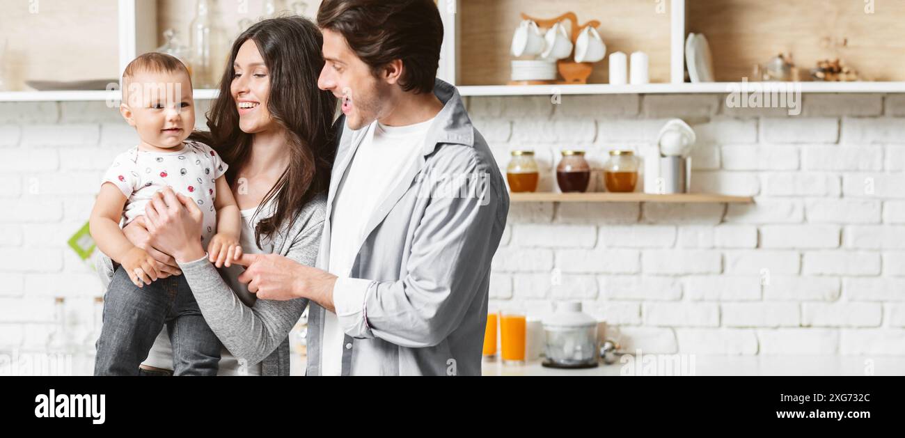 Happy Family Holding Baby In Kitchen With White Brick Wall Stock Photo ...