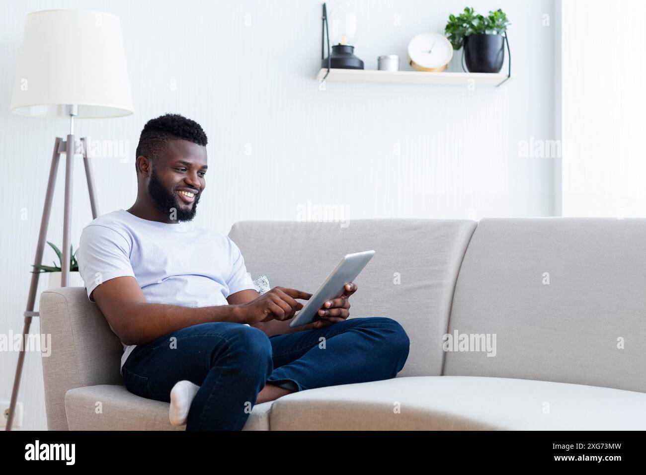 Man Using Tablet On Sofa In A Modern Living Room Stock Photo - Alamy