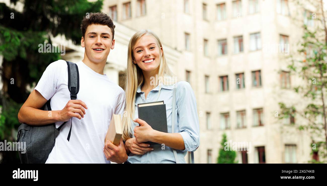 Happy university students holding books and smiling to camera Stock ...