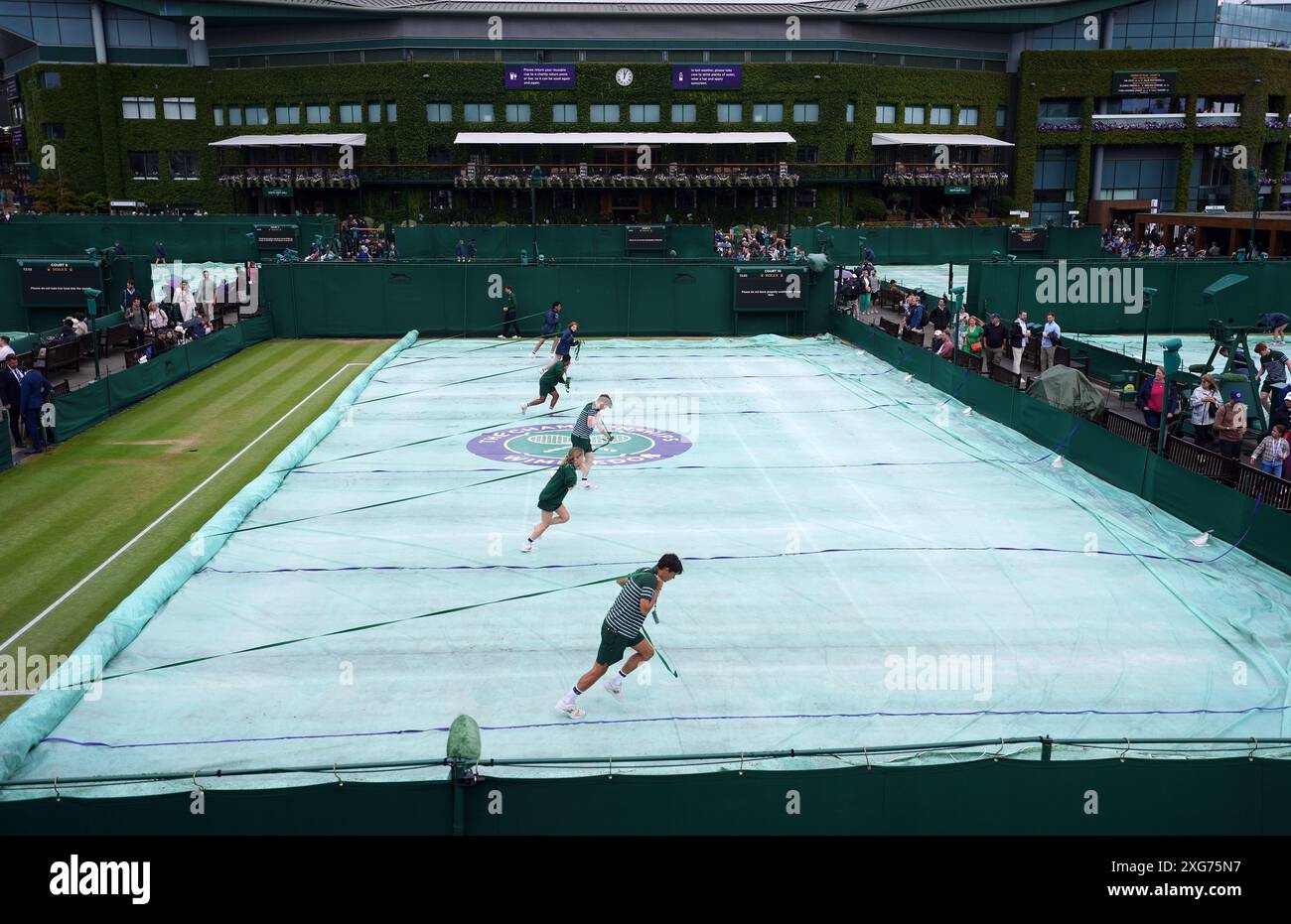 Ground staff remove the covers from the outside courts on day seven of ...