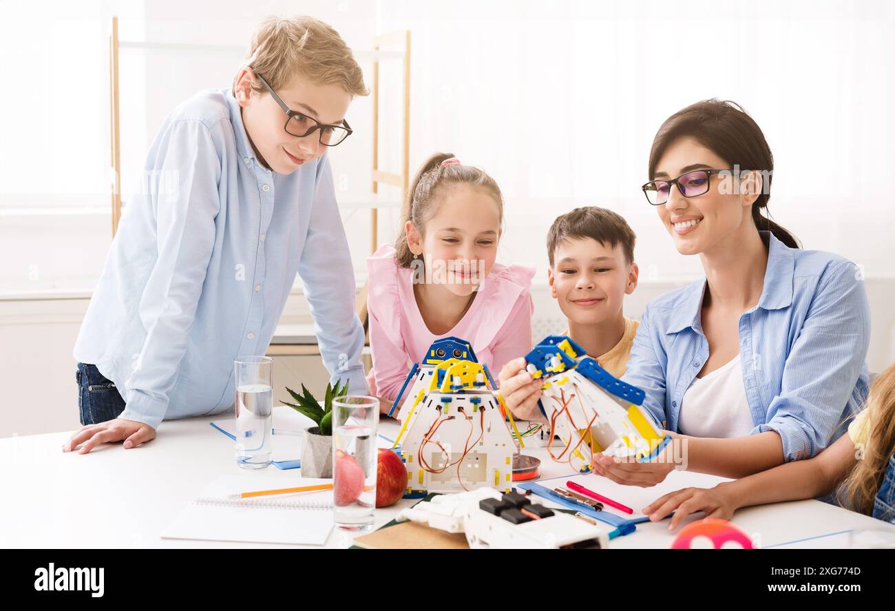 Teacher Assisting Students Building Robots During Class Stock Photo - Alamy