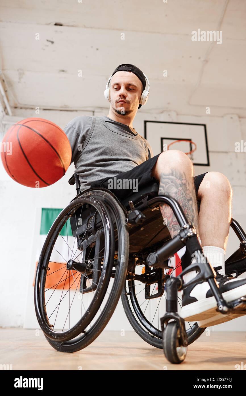 Vertical low angle shot of young sportsman with disability dribbling ...