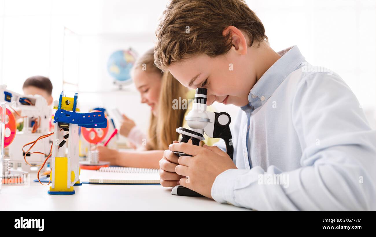 Young Boy Looking Through a Microscope in a Classroom Setting Stock ...
