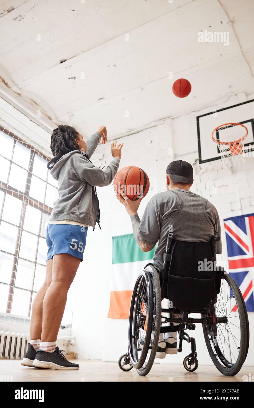 Vertical back view of sportsman using wheelchair in basketball practice ...
