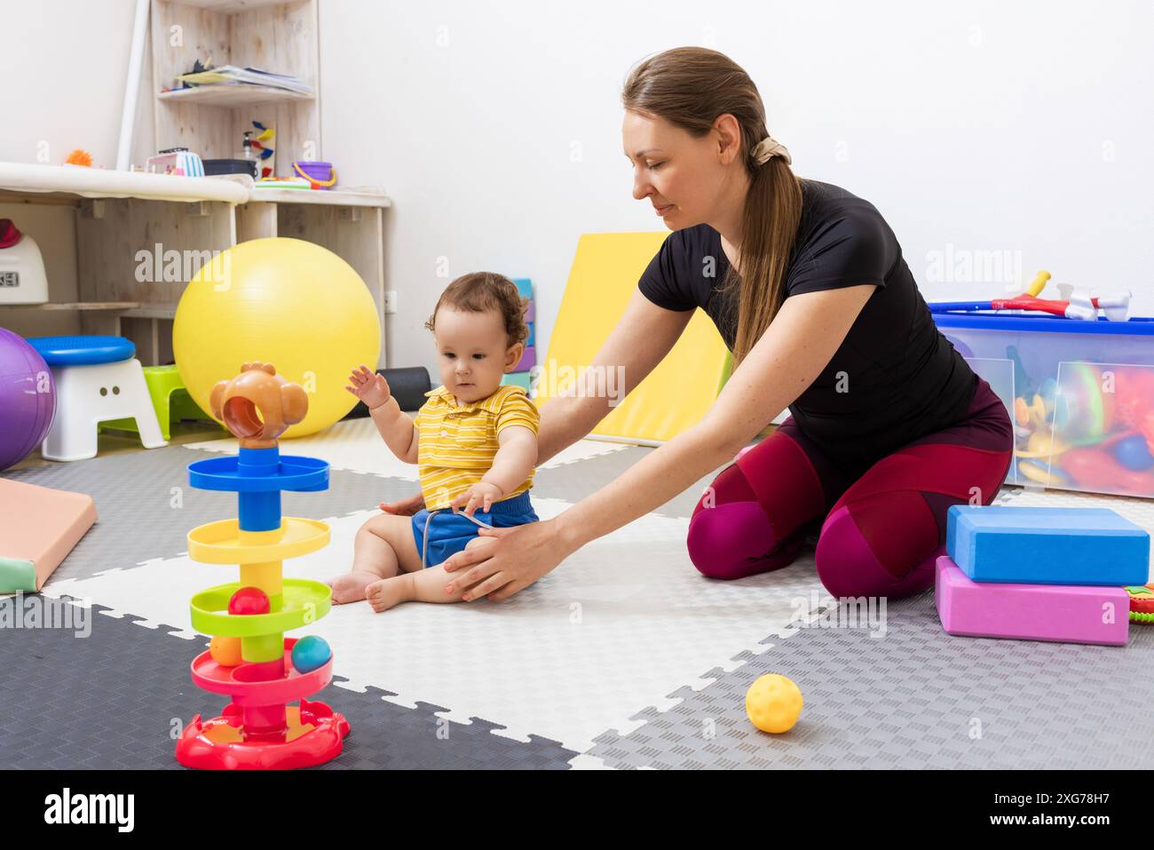 Physiotherapist assisting a little child with coordination disorders ...