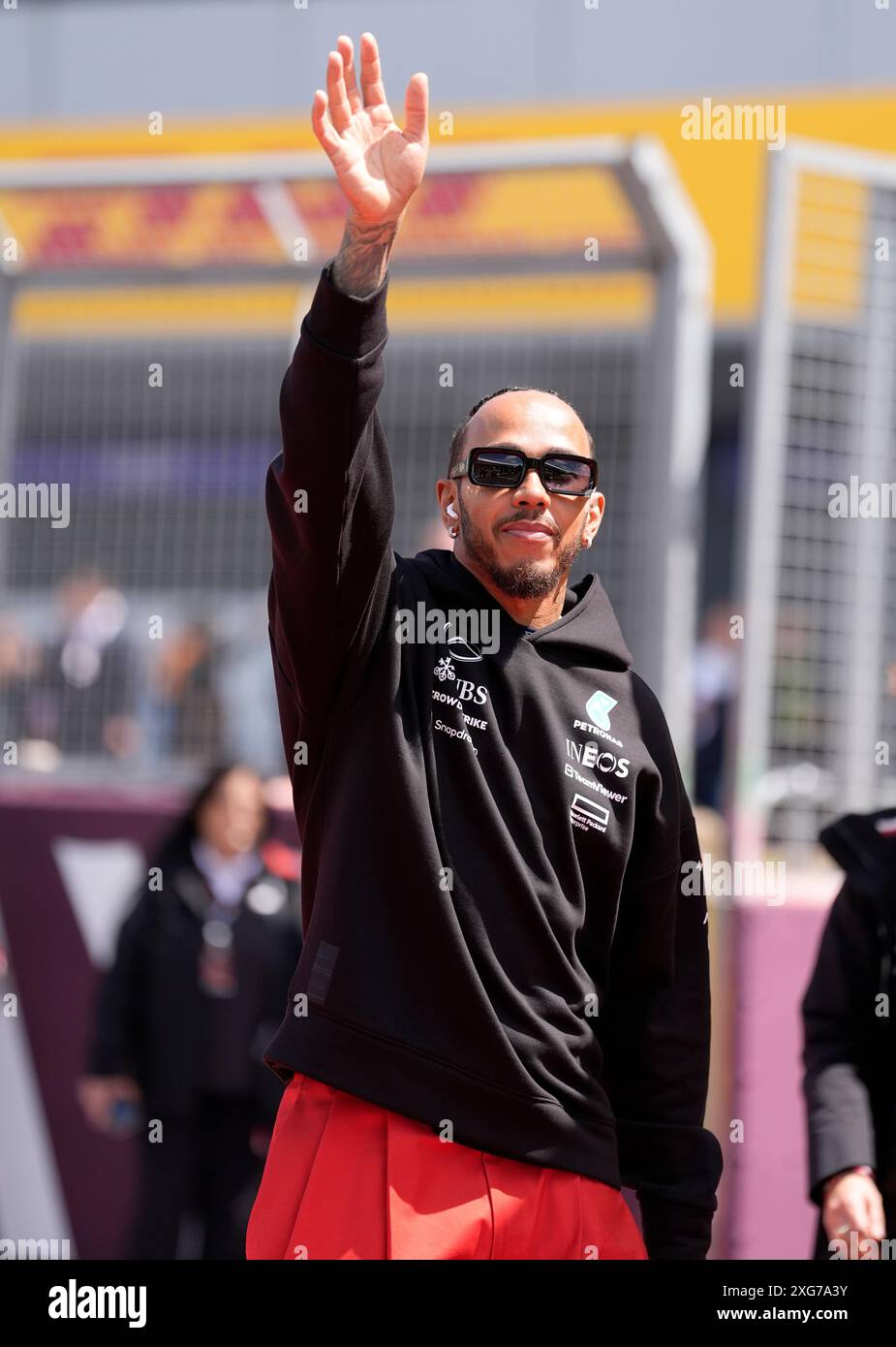 Mercedes driver Lewis Hamilton waves to fans as he arrives at the track ...