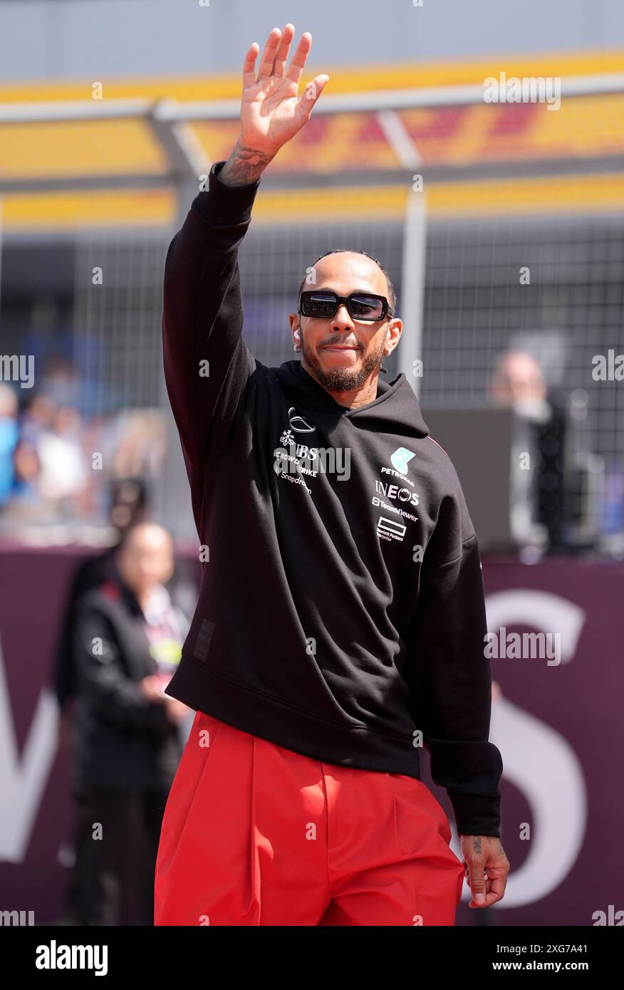 Mercedes driver Lewis Hamilton waves to fans as he arrives at the track ...