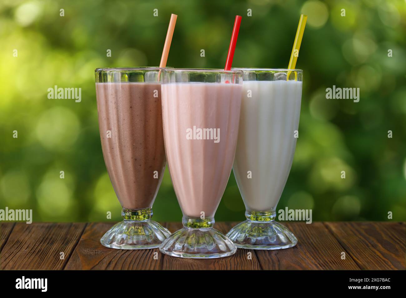 set of different delicious milkshakes in glasses with straw on table ...