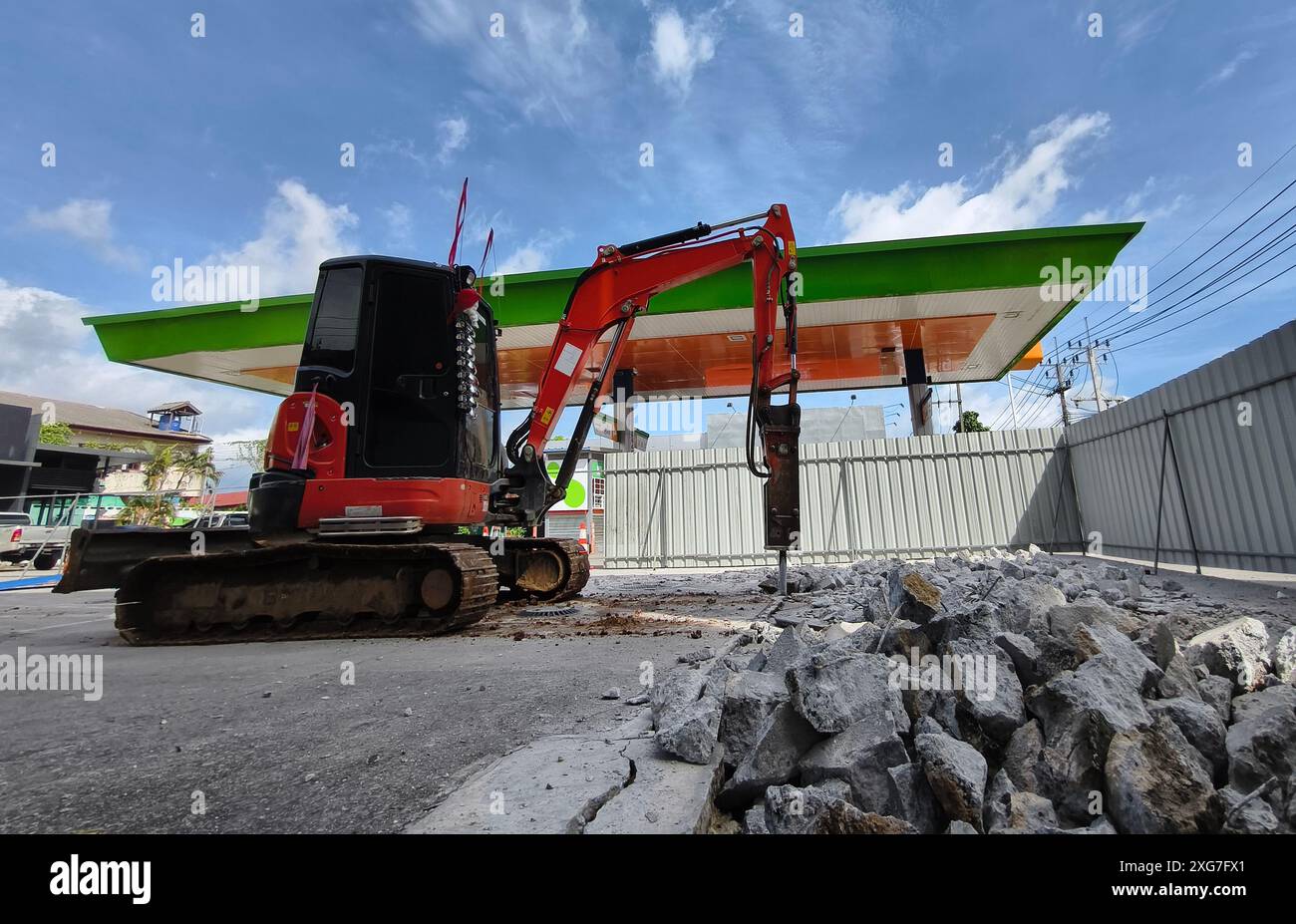 Excavator using hydraulic hammer for breaking concrete at a ...