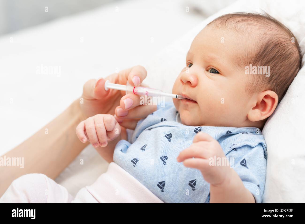 Mother feeding newborn baby with Vitamin K using plastic dropper to ...