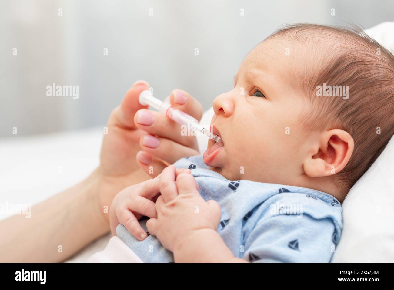 Mother feeding newborn baby with Vitamin K using plastic dropper to ...