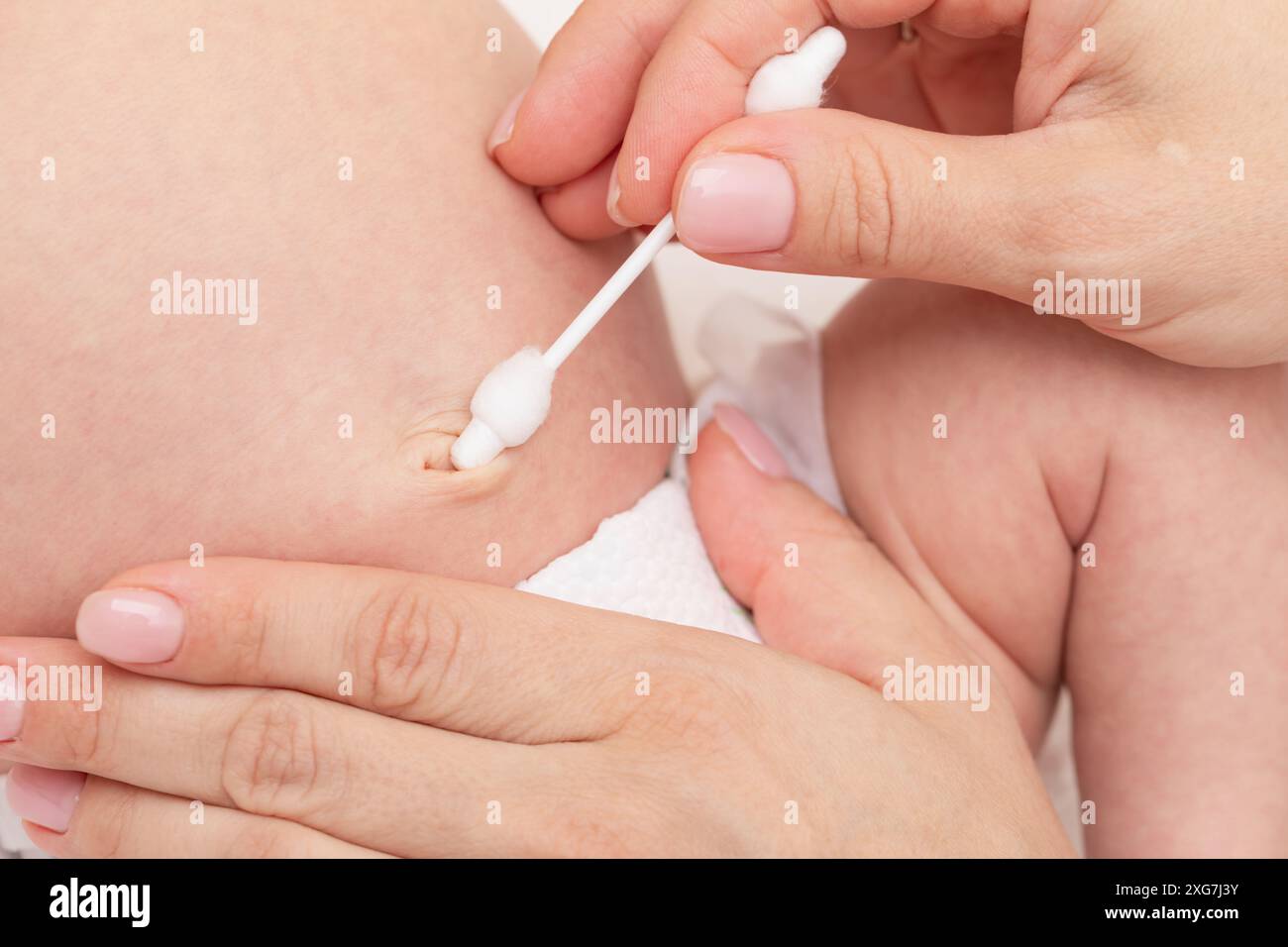 Close-up of mother or pediatrician wipes belly button of newborn baby ...