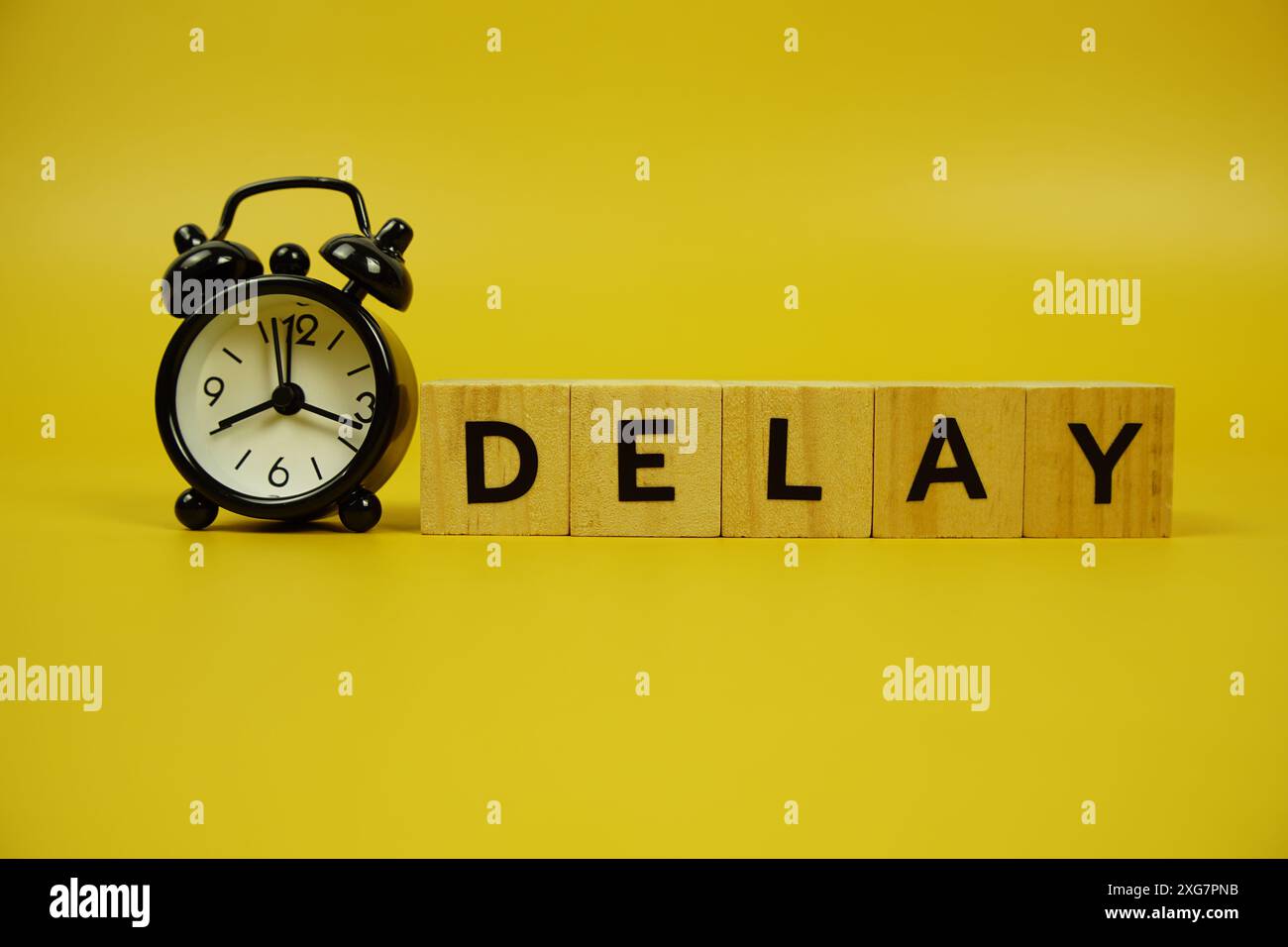 Delay with wooden blocks alphabet letters and alarm clock on yellow ...