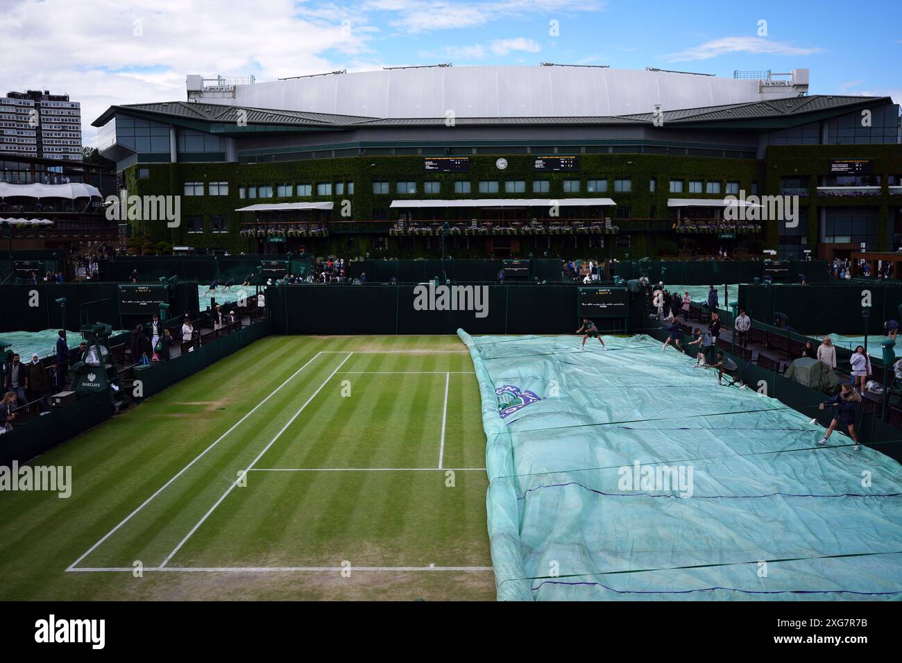 Ground staff remove the covers from a court on day seven of the 2024 ...