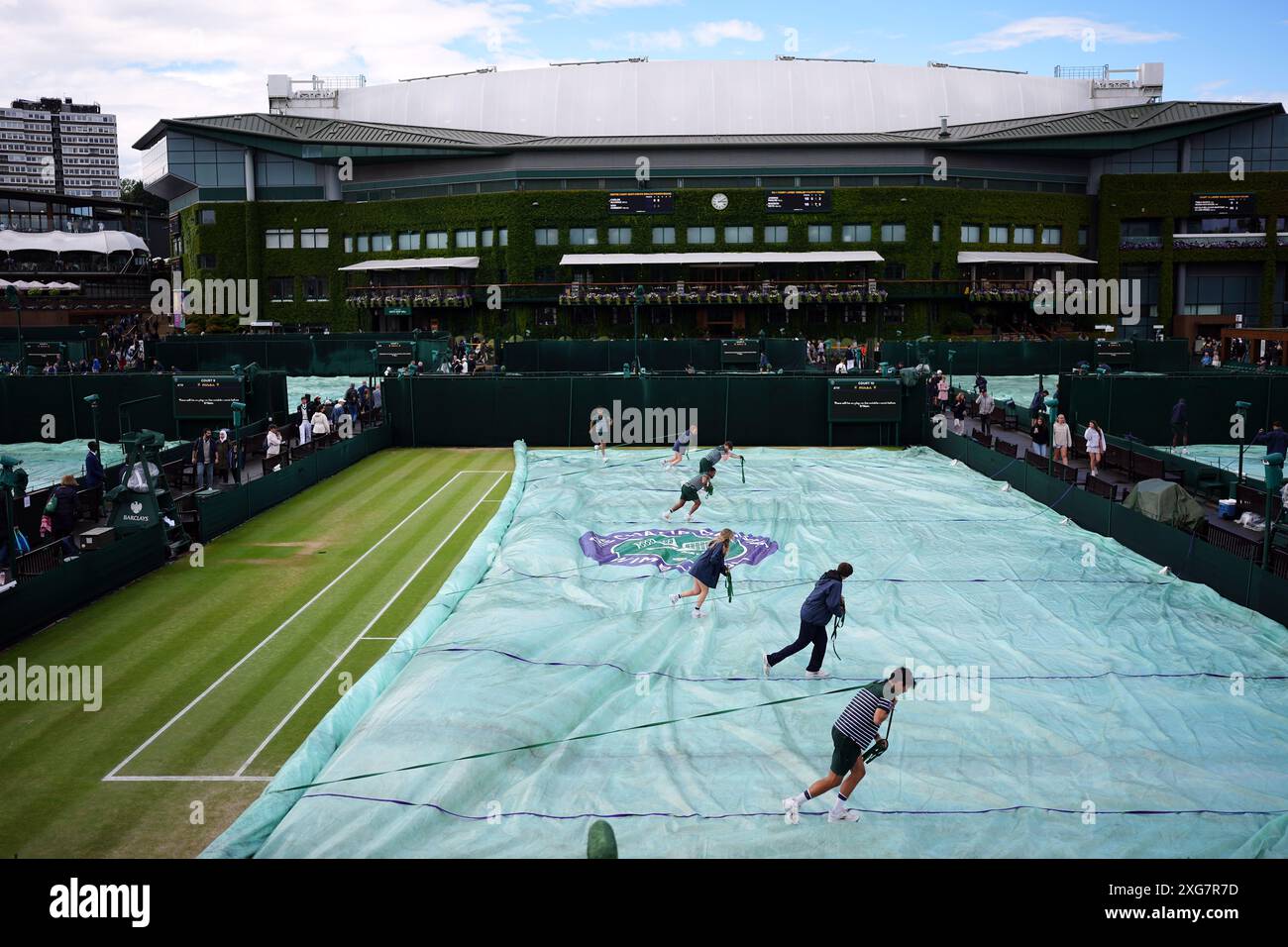 Ground staff remove the covers from a court on day seven of the 2024 ...