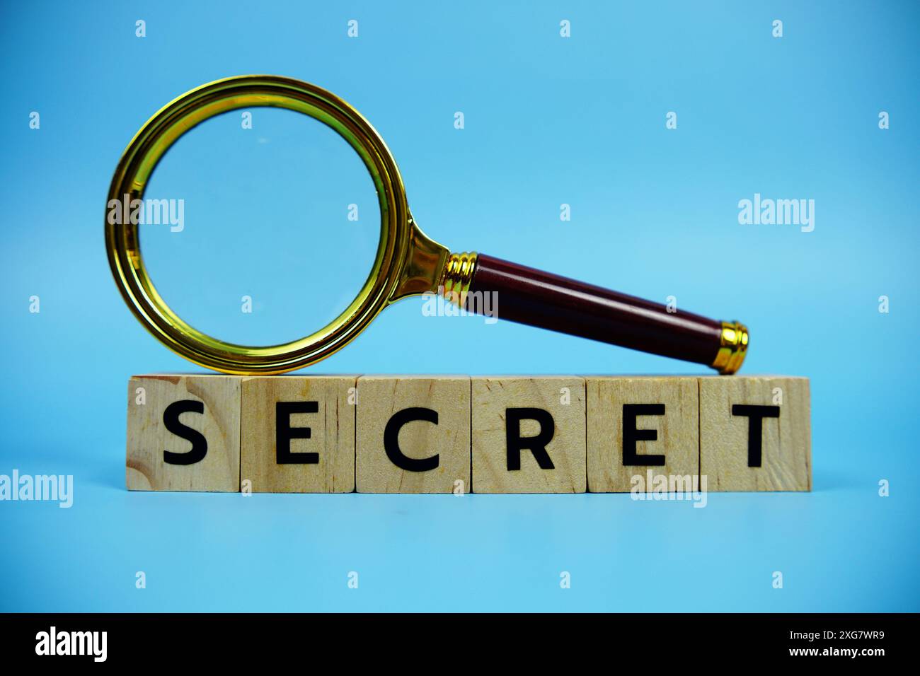 Secret with wooden blocks alphabet letters and Magnifying glass on blue ...